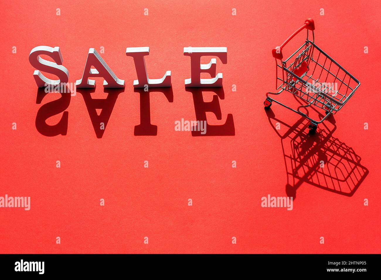 Small empty shopping trolley cart and word SALE of white letters casts ...