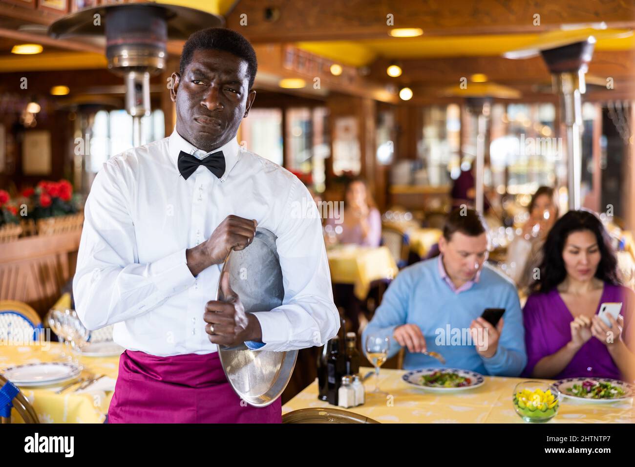 Tired african american waiter with empty serving tray in restaurant ...