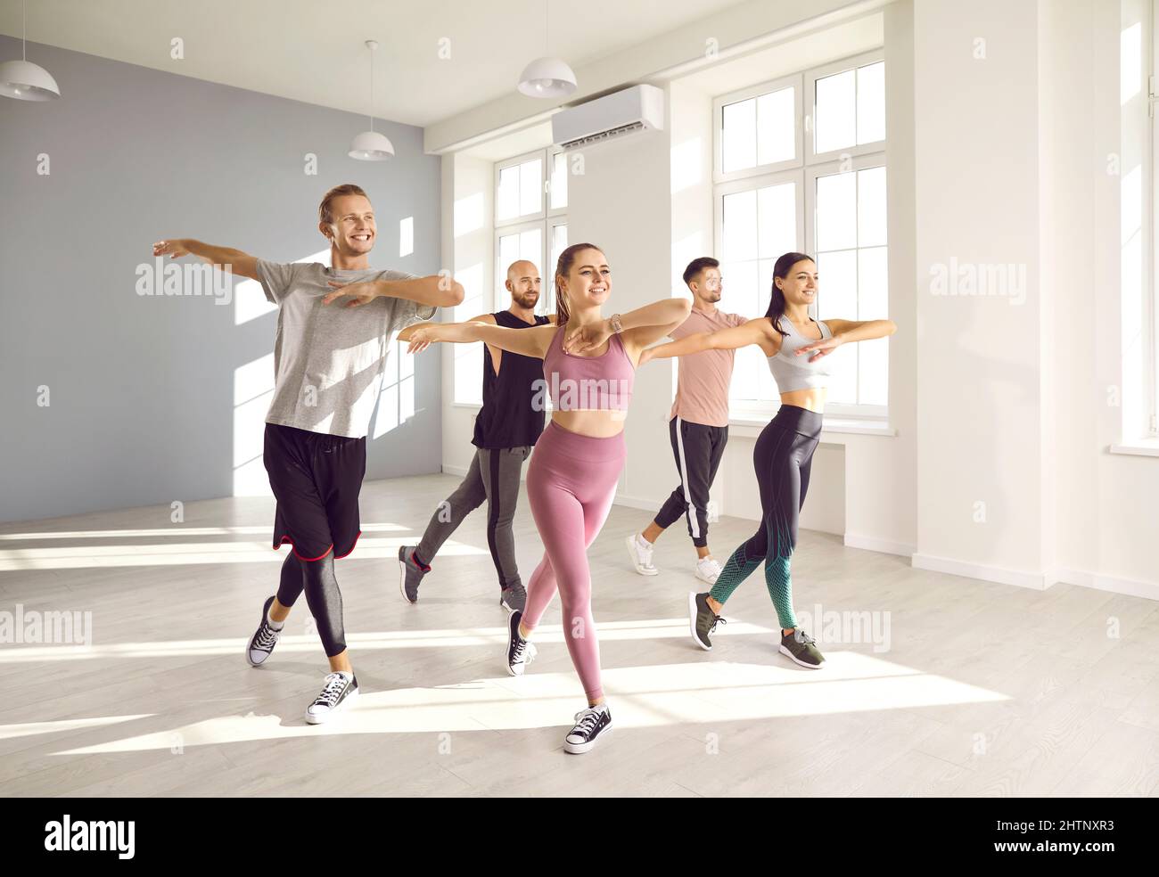 Group of happy, smiling young people having a workout class with a ...