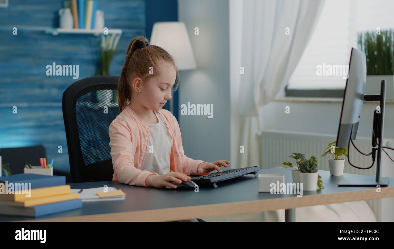 Pupil using keyboard and computer for online class lessons at desk ...
