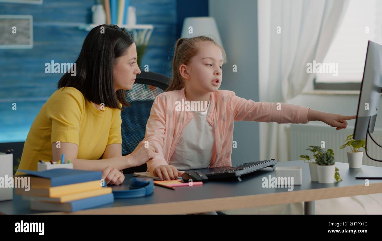Child receiving assistance for online task from mother on computer at ...