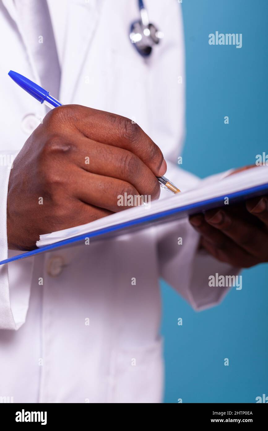 Closeup of african american doctor hand holding ballpoint pen writting ...