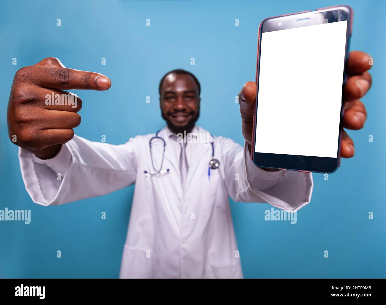 Closeup of smiling medical doctor pointing finger at smartphone with ...