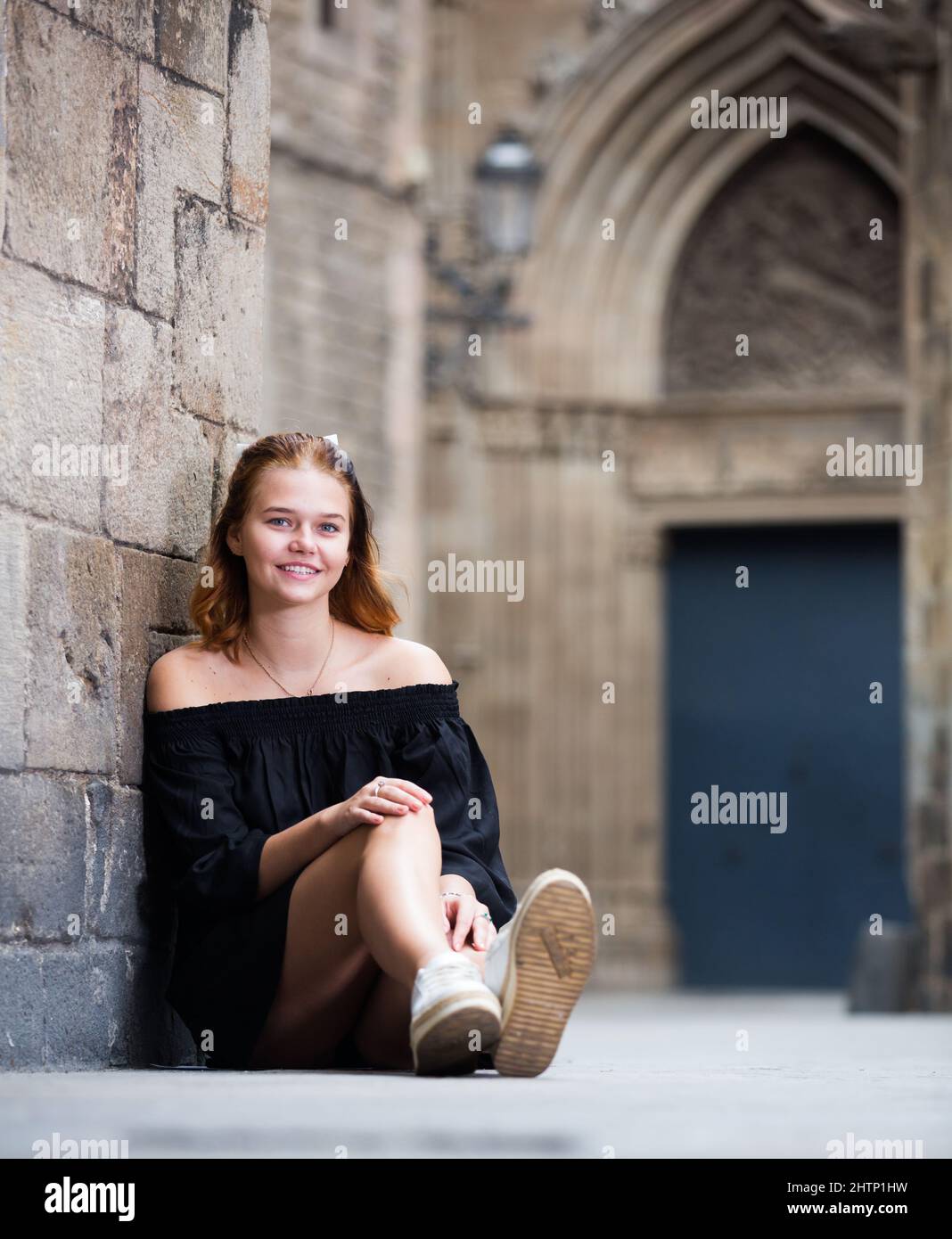 Cheerful girl sitting in dress outdoors Stock Photo - Alamy