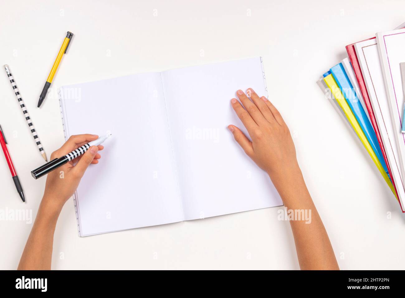Kid hand holding pen in left hand and writing in open notebook, doing ...