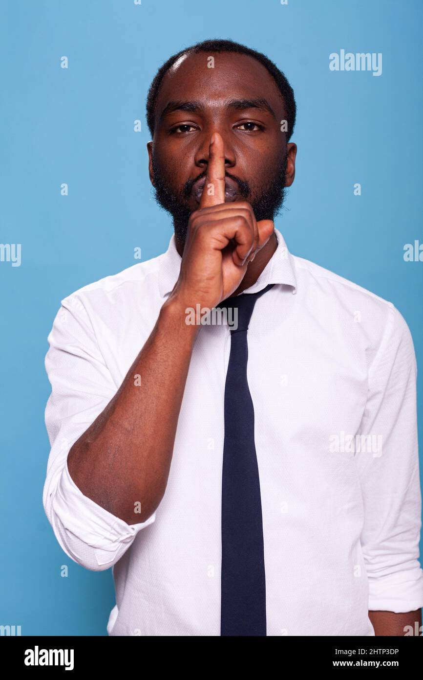 Portrait of african american man doing hush sign with index finger over ...