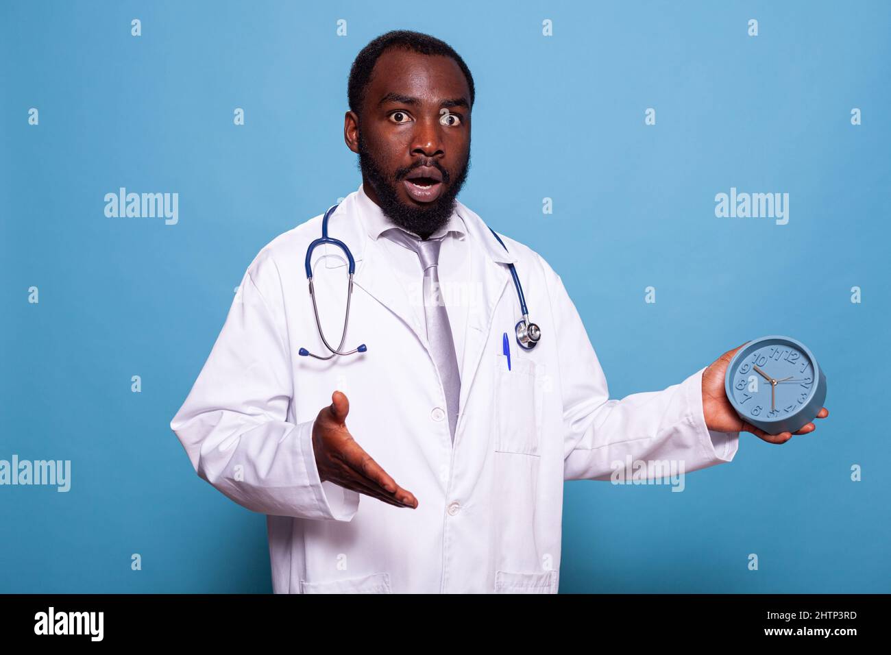 Medical doctor looking shocked running out of time holding alarm clock ...