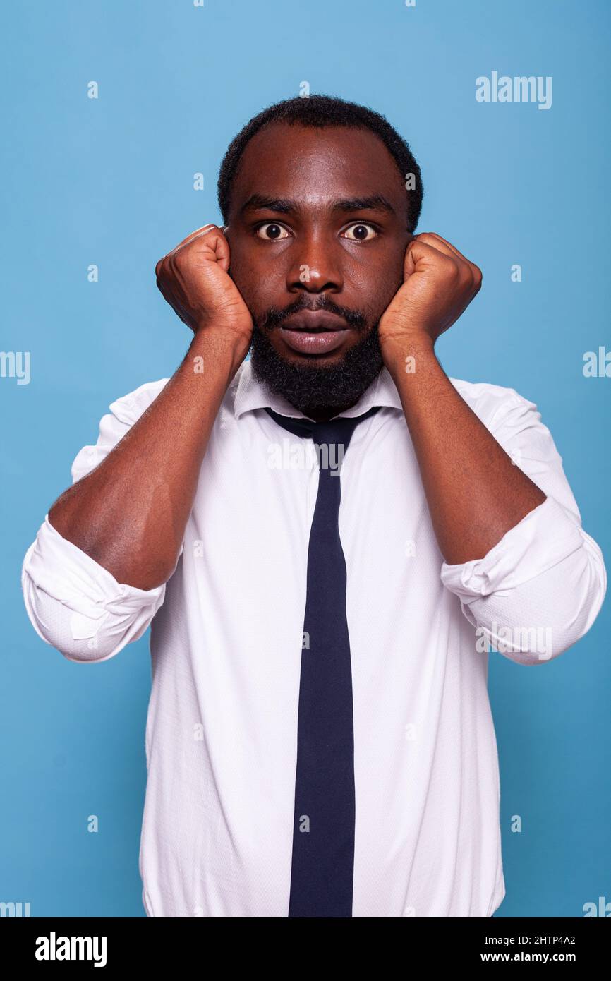 Nervous entrepreneur with open eyes holding face in closed palms over ...