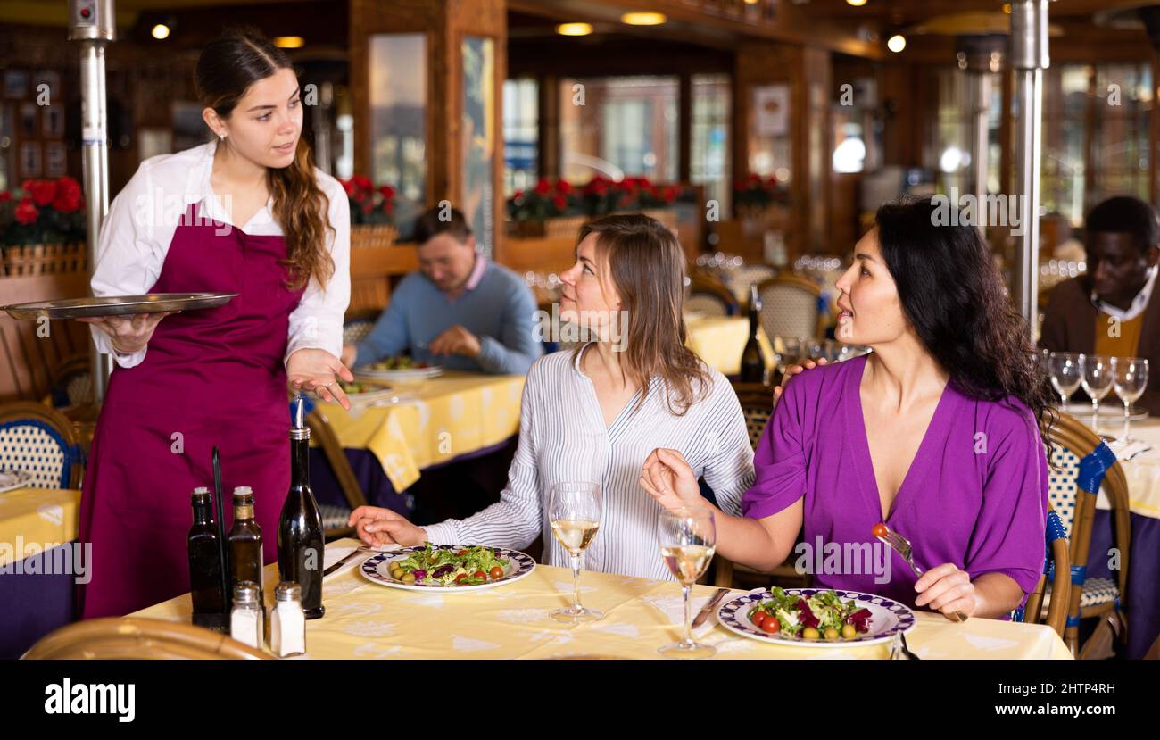 Two women talking with waitress in restaurant Stock Photo - Alamy