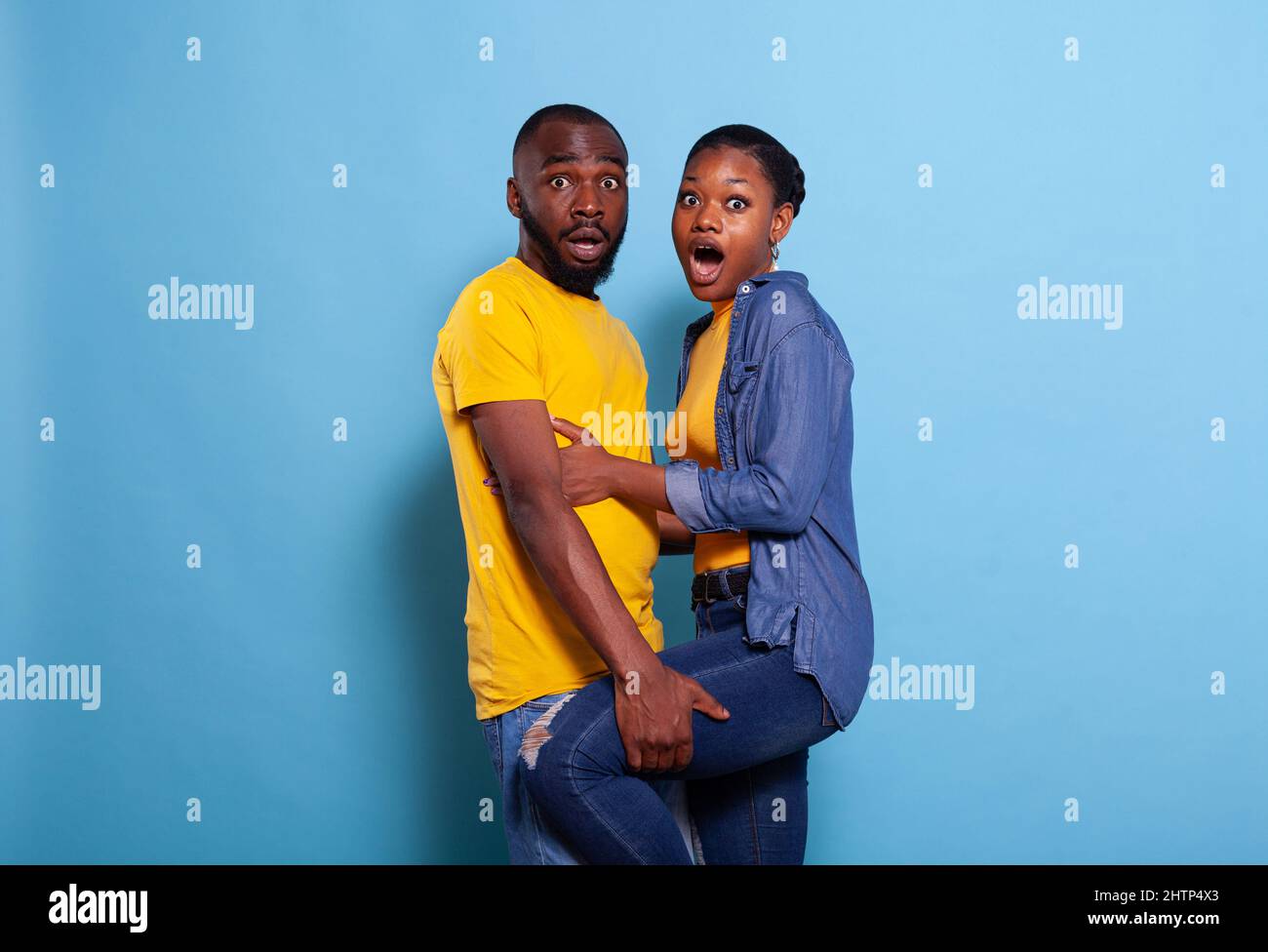Astonished couple embracing each other in front of camera, having ...