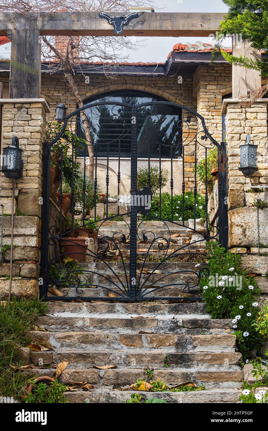 close-up of a beautiful forged gate leading to an old stone house by ...