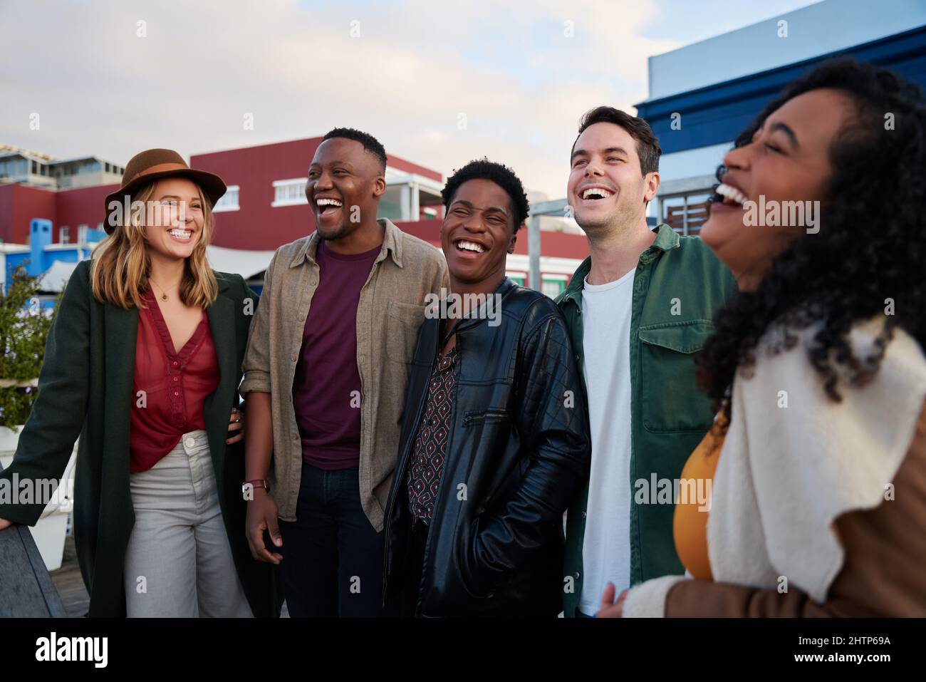 Stylish, diverse group of friends standing together on rooftop at party ...
