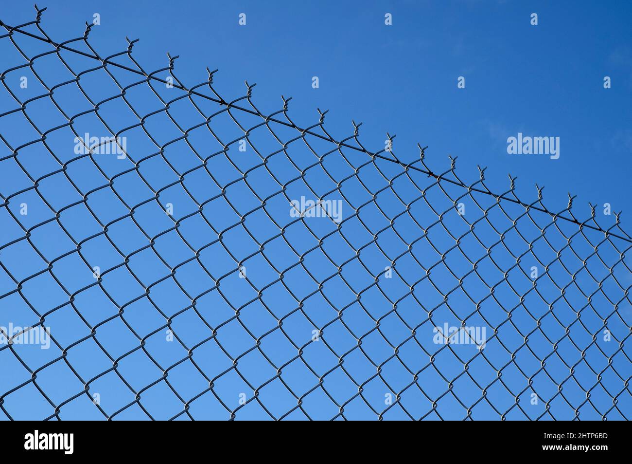 metal chain link fence on blue sky background Stock Photo - Alamy