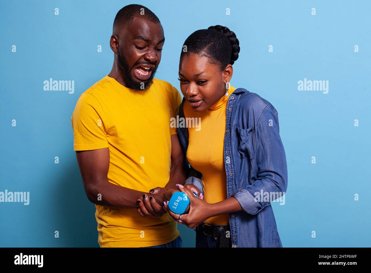 African american couple trying to lift dumbbells in studio. Boyfriend ...