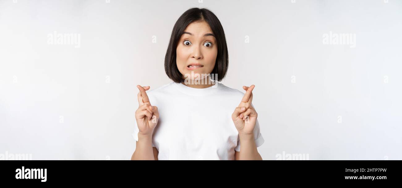 Hopeful asian girl cross fingers, making wish, anticipating, wishing ...