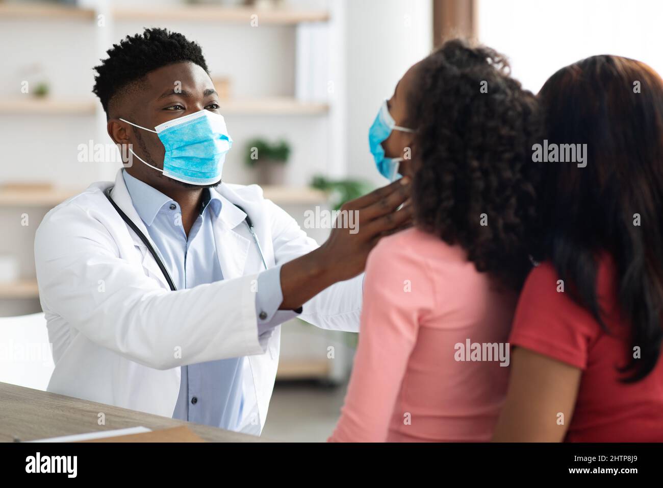 Black doctor in face mask checking little patient tonsils Stock Photo ...