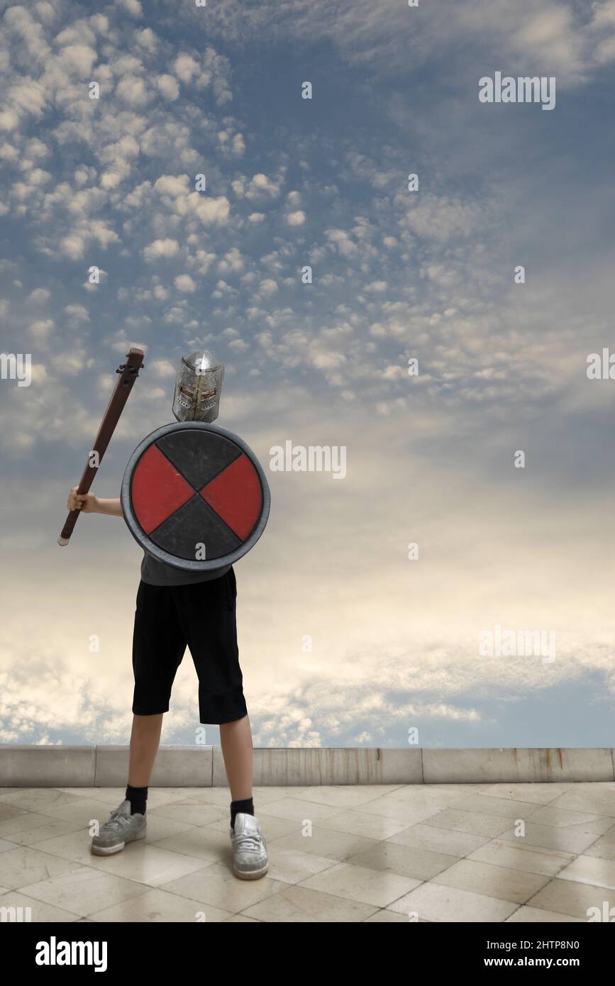 A vertical shot of a warrior with a shield standing on a cloudy sky ...