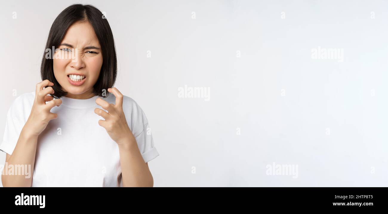 Angry asian woman cursing, looking outraged and annoyed, clench teeth ...