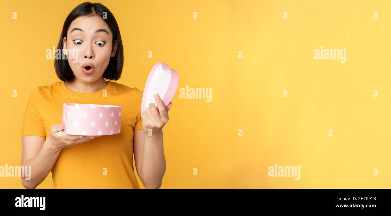 Portrait of excited asian woman, open gift box with surprised happy ...