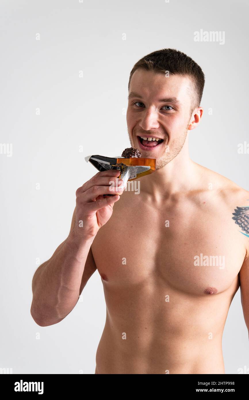 Man eats protein bar on white background isolated young background ...
