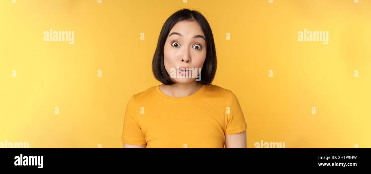 Close up portrait of asian girl showing surprised reaction, raising ...