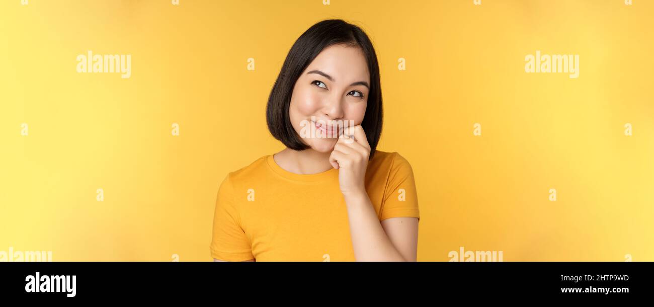 Close up portrait of cute asian girl smiling, thinking, looking up ...