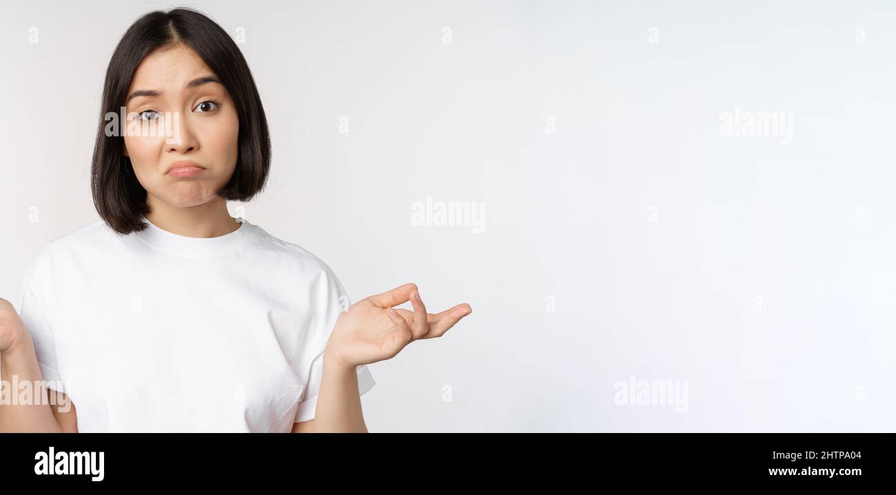 Portrait of confused asian woman shrugging shoulders, looking clueless ...