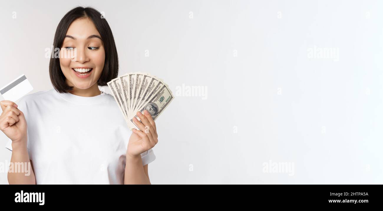 Portrait of asian woman smiling, holding credit card and money cash ...