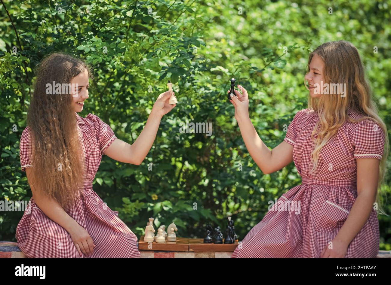 two teen girls play chess in retro dress outdoor, childhood Stock Photo ...