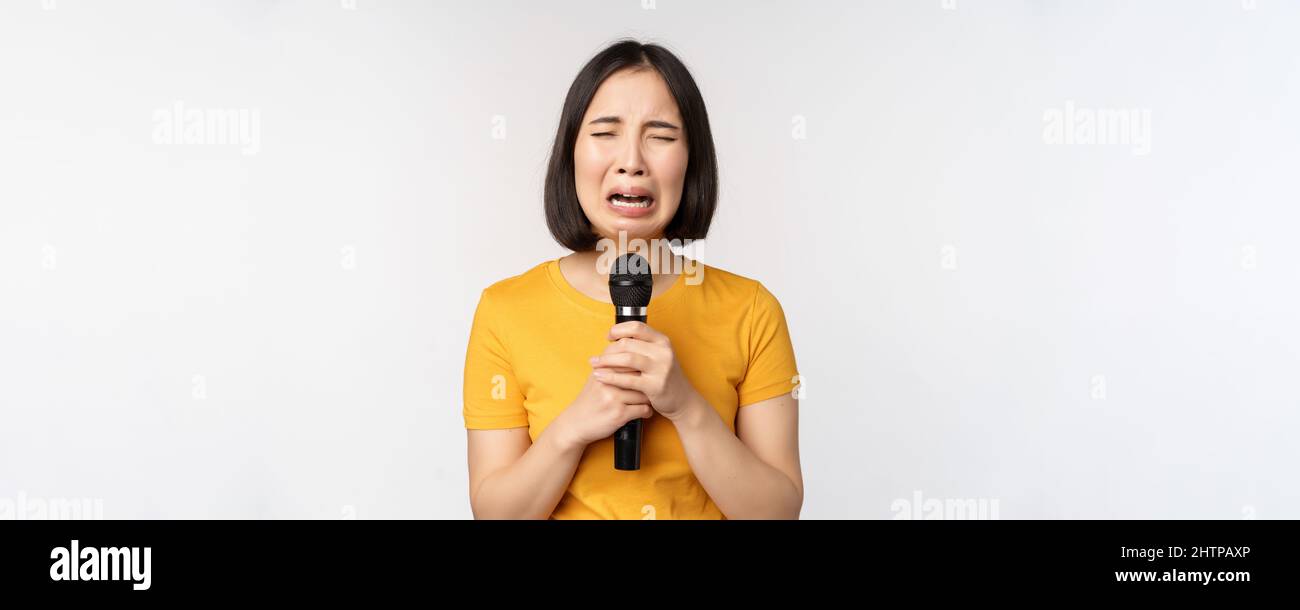 Crying asian girl singing heartbroken in microphone, holding mic and ...
