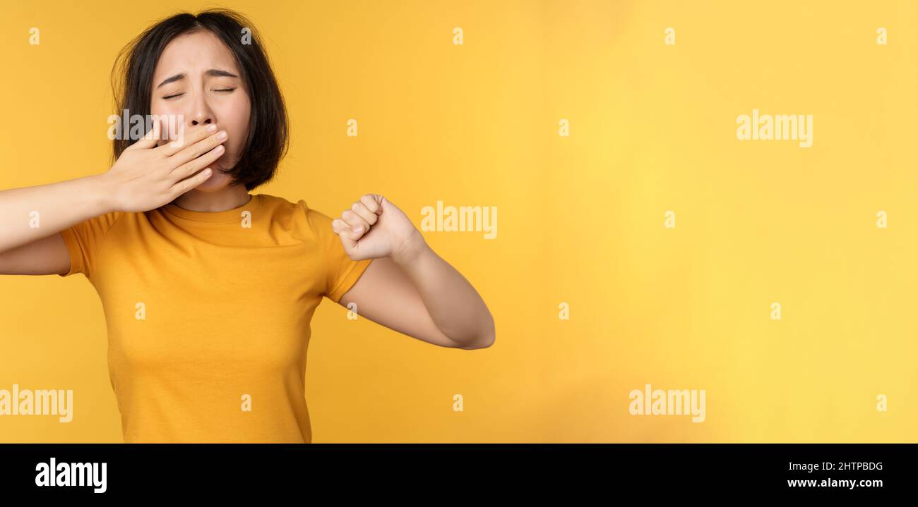 Image of young asian girl student, yawning, feeling tired, standing ...