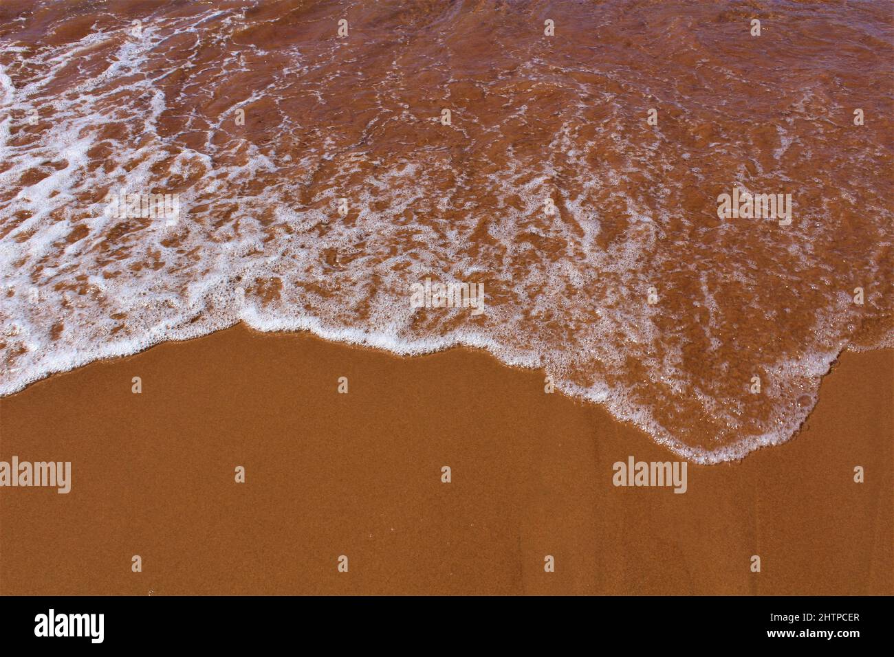 Ocean water washing over red sand background texture (PEI, Canada Stock ...
