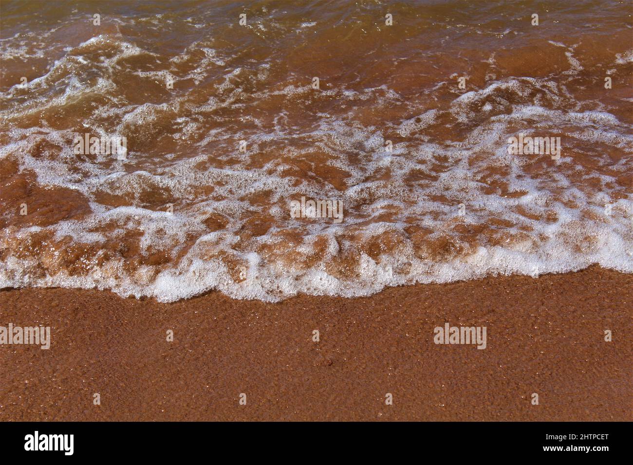 Ocean water washing over red sand background texture (PEI, Canada Stock ...