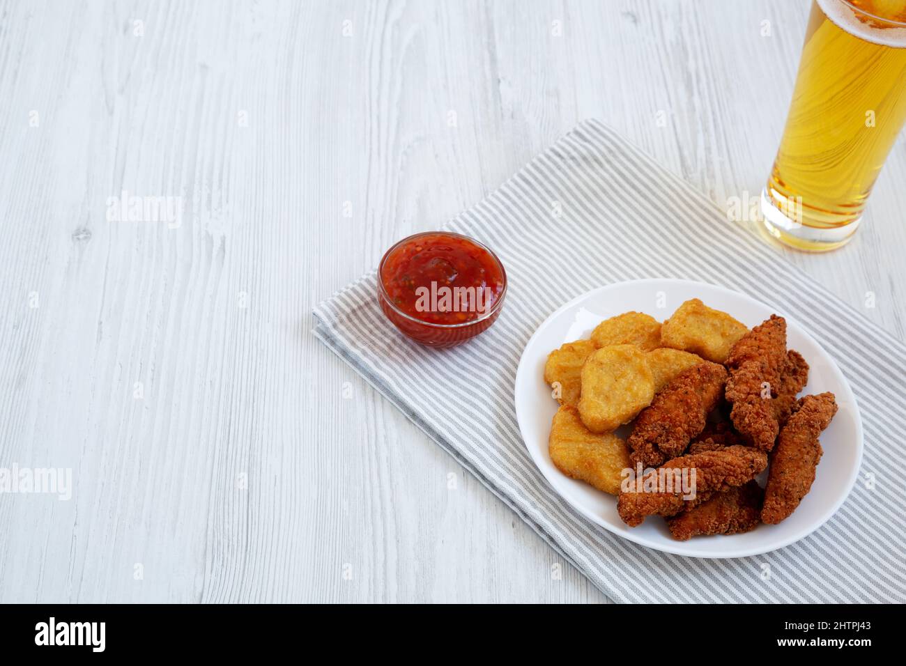 Homemade Nuggets and Chicken Tenders with Sauce and Beer, side view ...