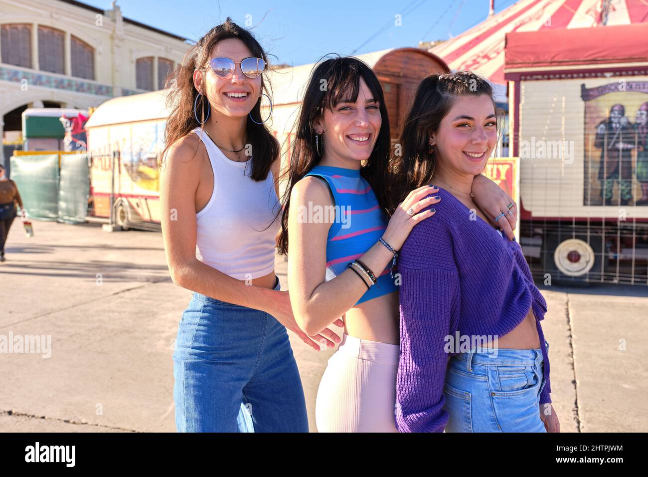Three friends posing while looking to the camera next to a circus Stock ...