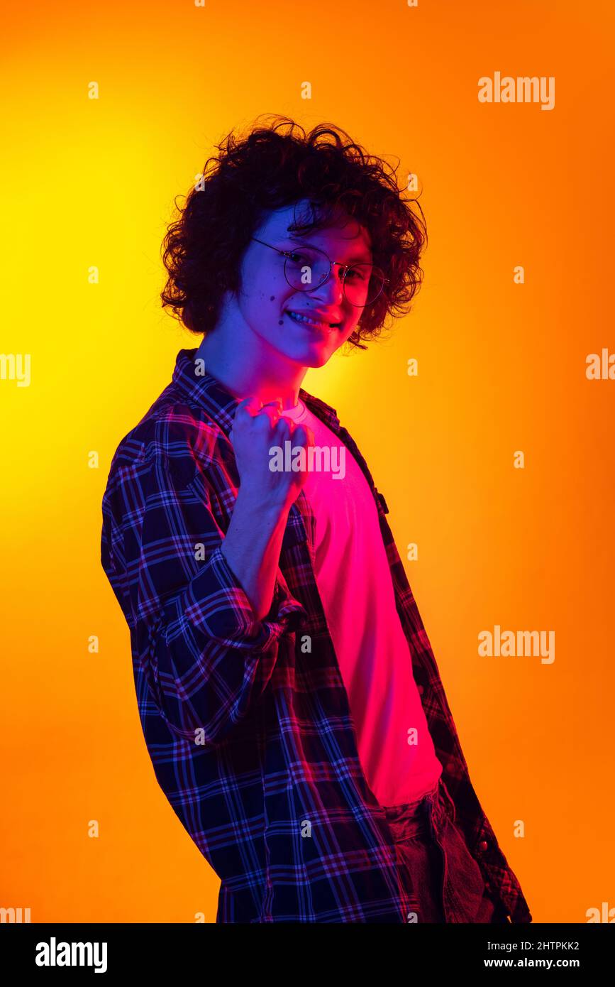 Half-length portrait of young curly man in checkered shirt looking at ...