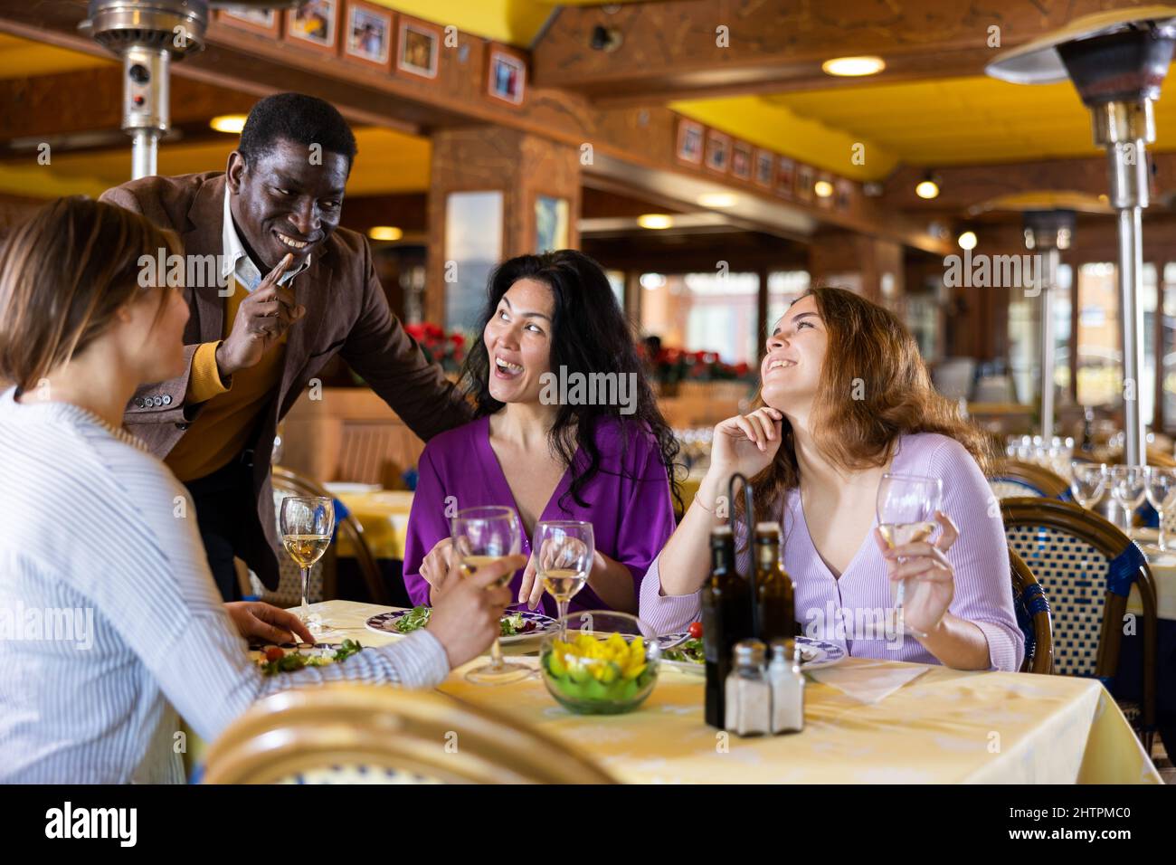 Smiling men invite women to dine for their table in restaurant Stock ...