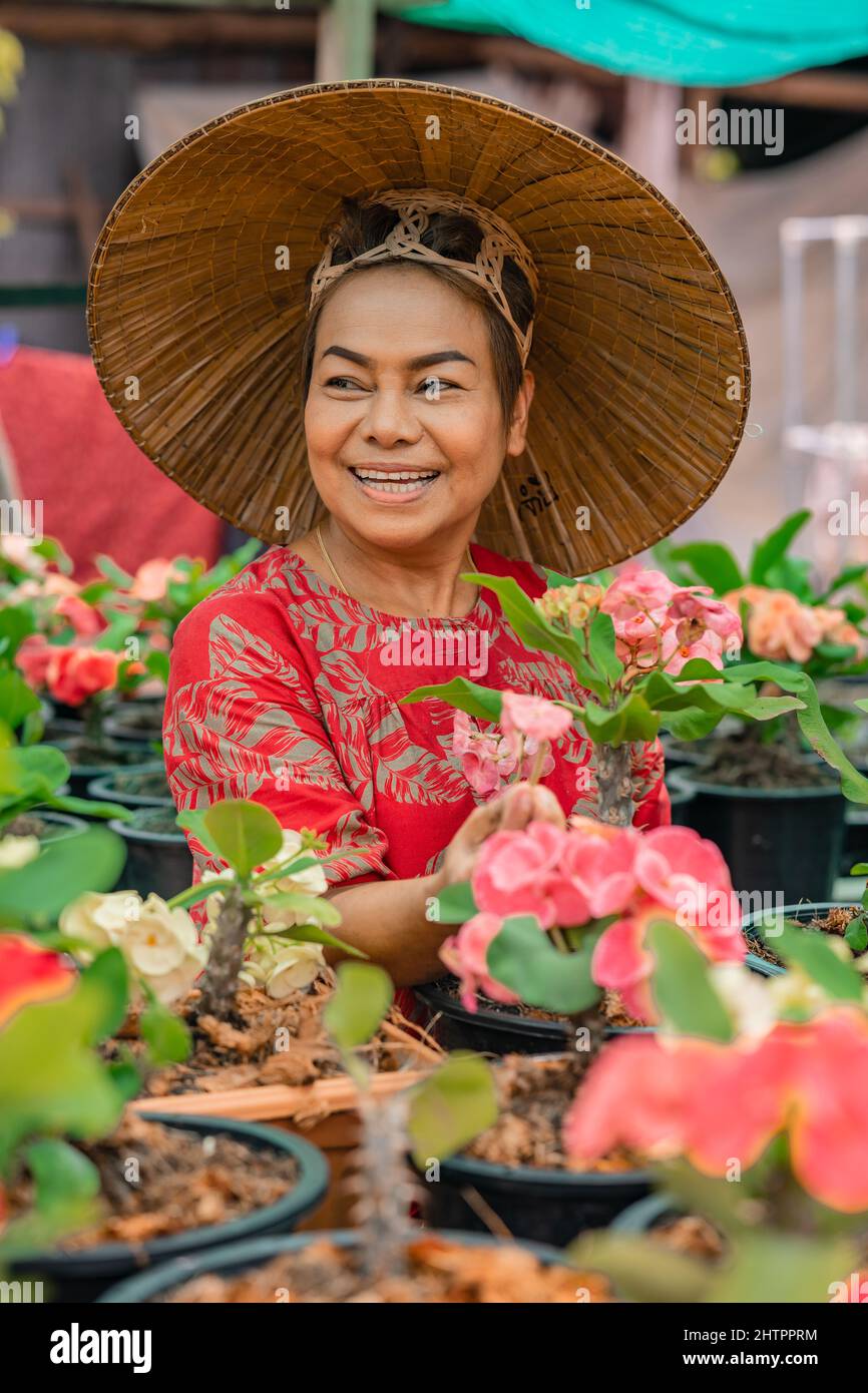 Asian Woman In Vietnamese Straw Hat Smiling Holding Potted Flower In