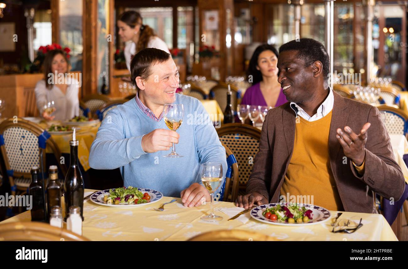 Two men drinking wine and talking in restaurant Stock Photo - Alamy