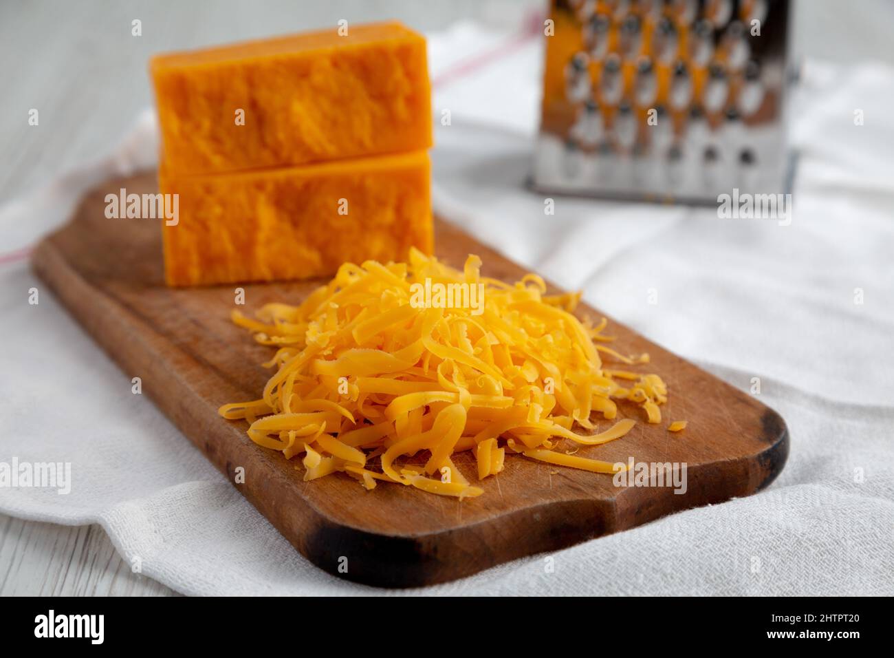 Shredded Sharp Cheddar Cheese on a rustic wooden board, side view ...