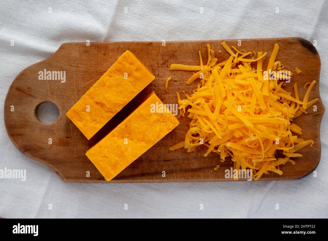 Shredded Sharp Cheddar Cheese on a rustic wooden board, top view. Flat ...