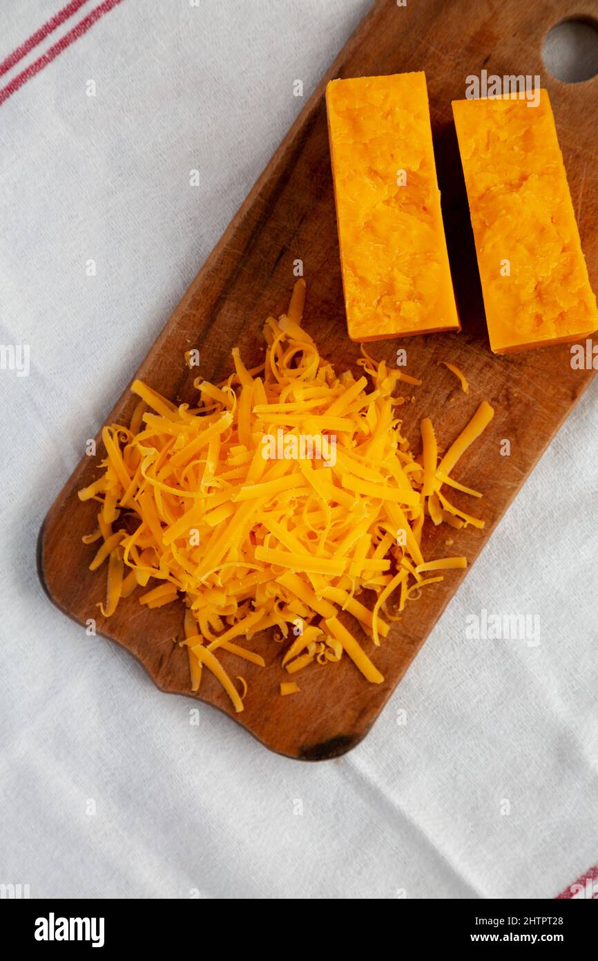 Shredded Sharp Cheddar Cheese on a rustic wooden board, top view. Flat ...
