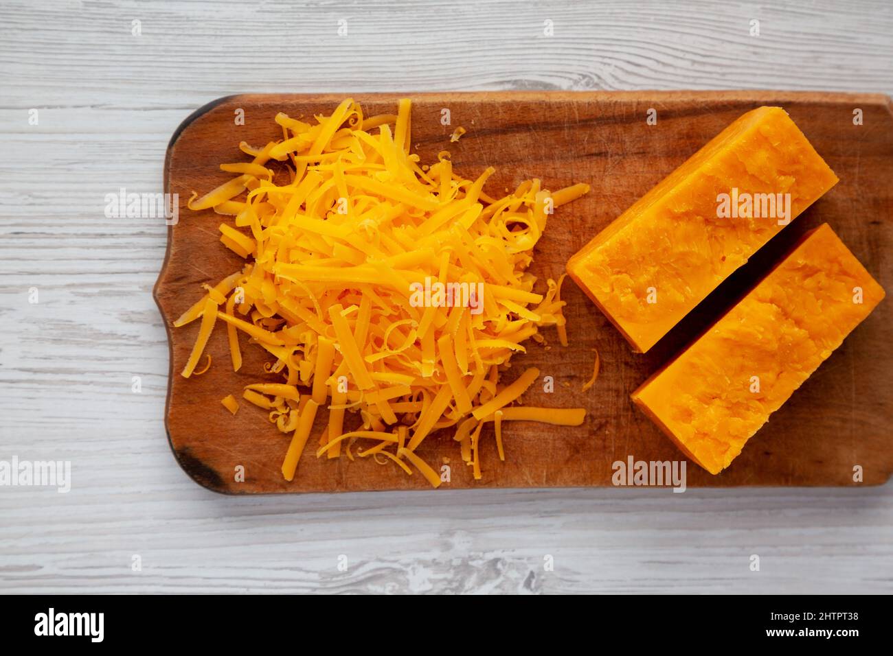 Shredded Sharp Cheddar Cheese on a rustic wooden board on a white ...
