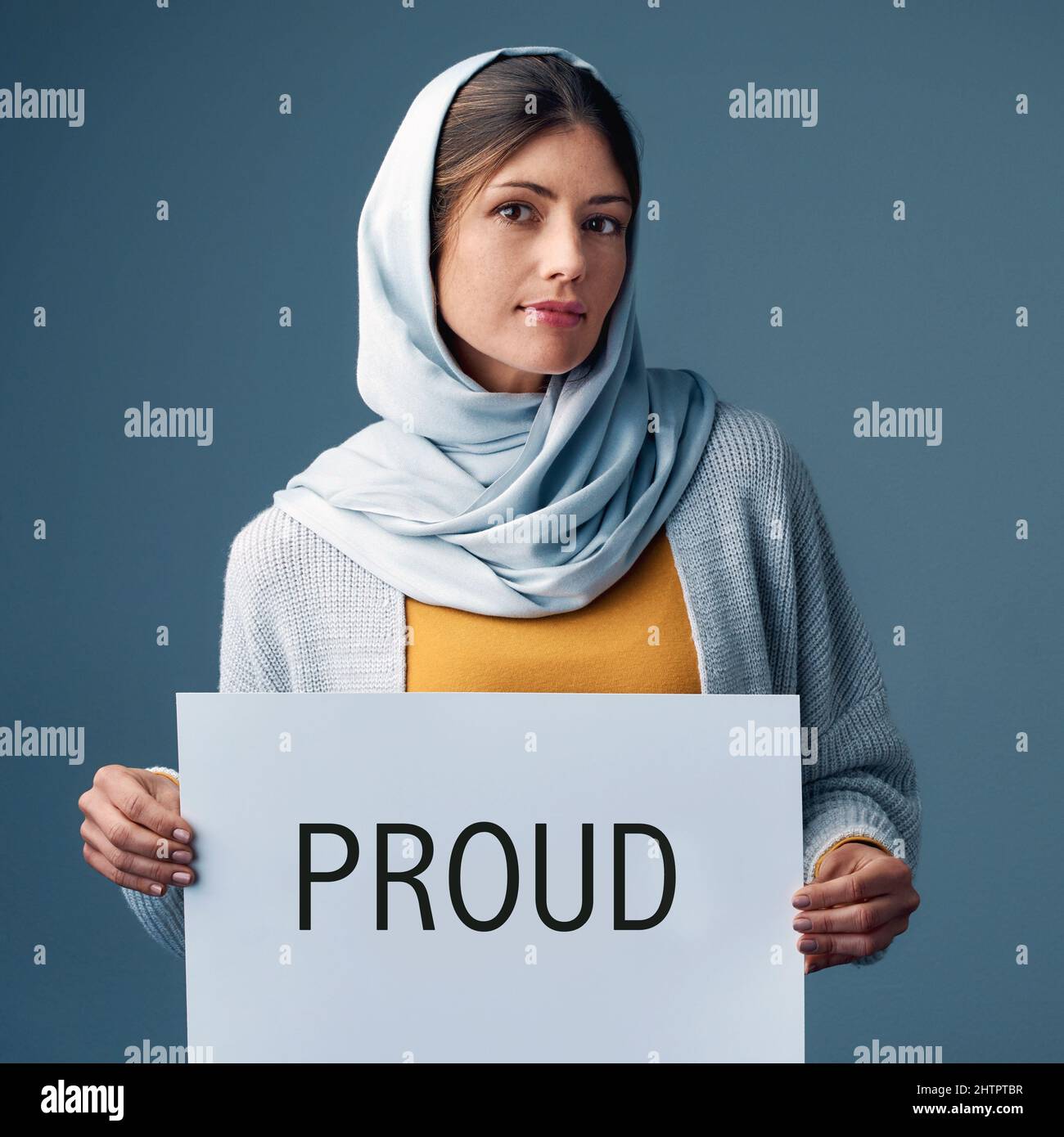 Proud. Studio portrait of an attractive young woman holding up a sign ...