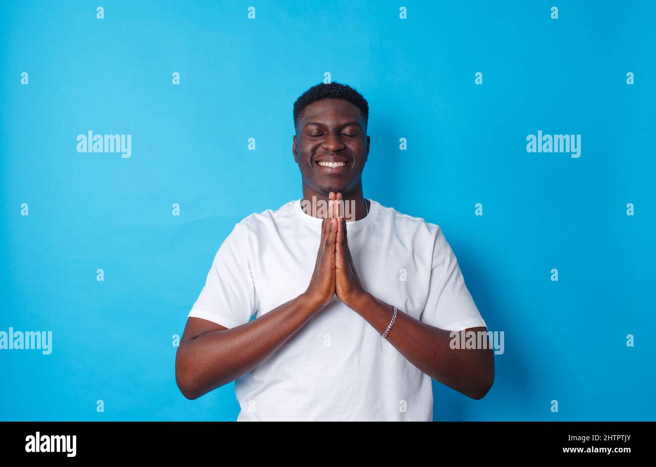 a picture of a smiling African man in a white T-shirt, cupping his ...