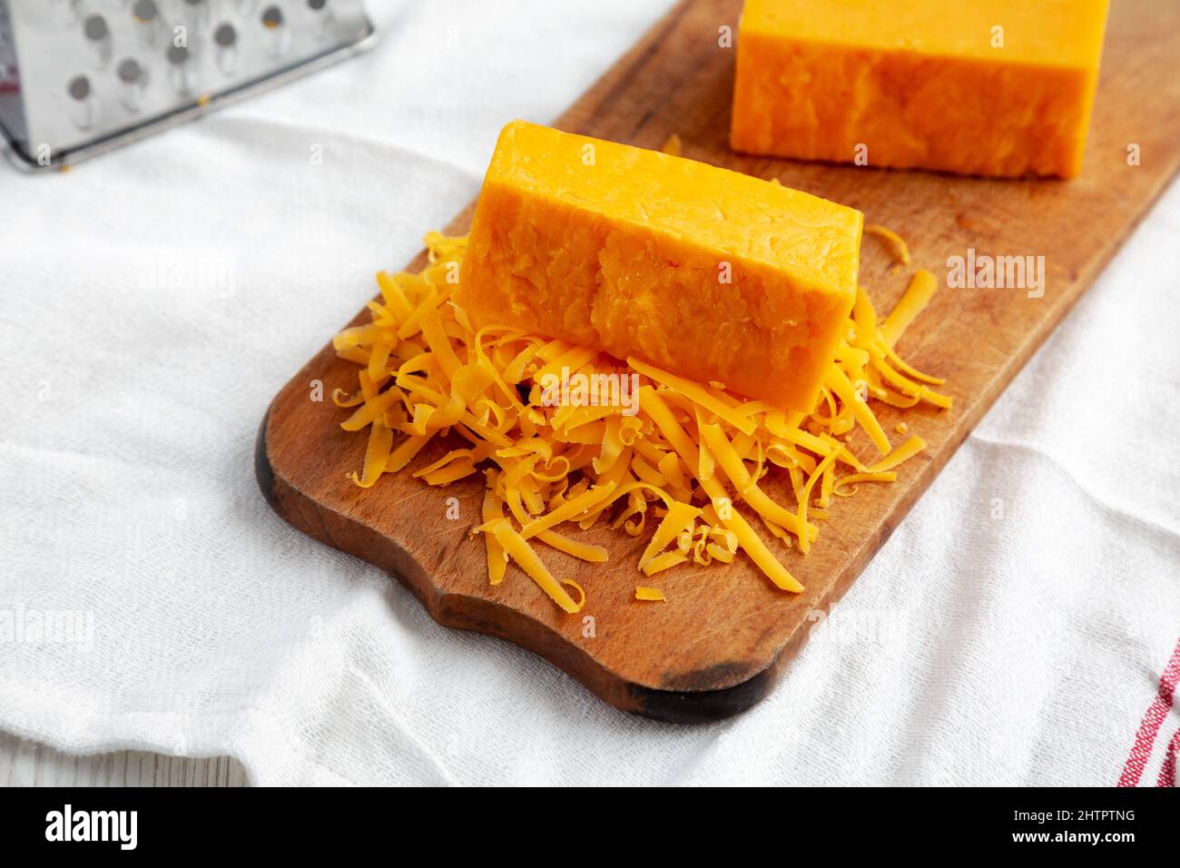 Shredded Sharp Cheddar Cheese on a rustic wooden board, side view Stock ...