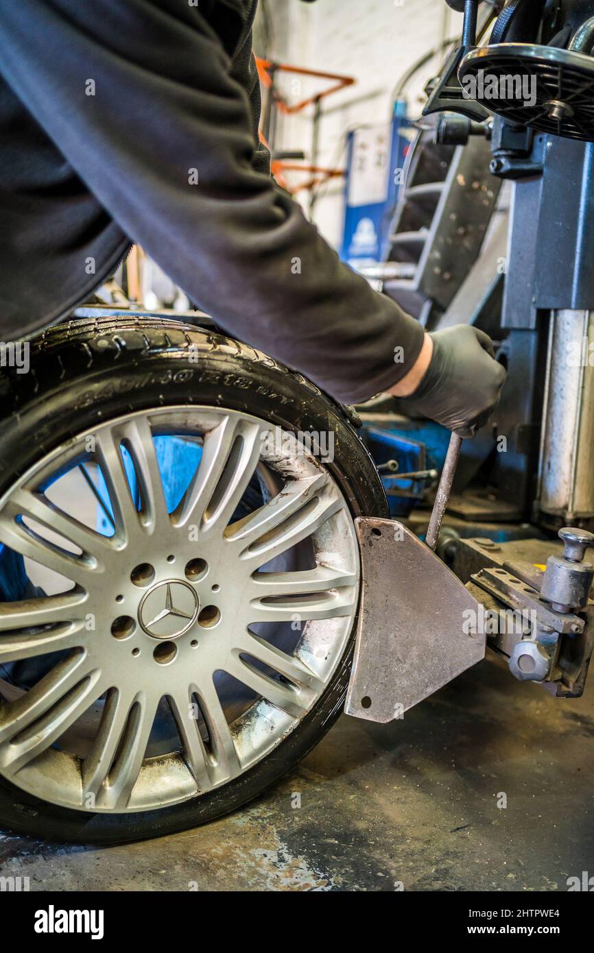 Tyre garage workshop. Garage staff fremove a tyre on an alloy wheel ...