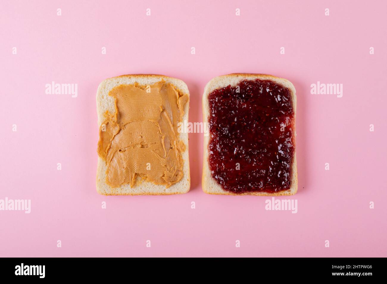 Directly above shot of peanut butter and preserves on bread slices over ...