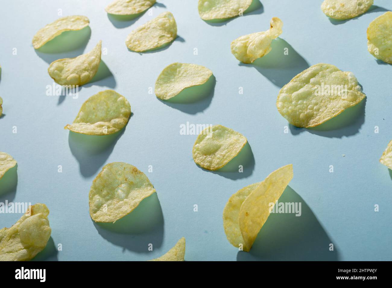 Full frame shot of potato chips arranged on blue background with shadow ...