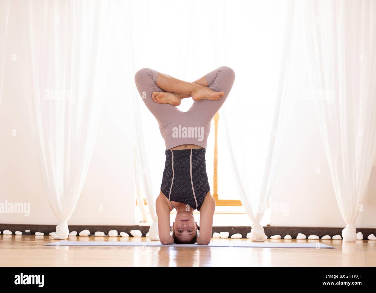 Young woman doing urdhva padmasana in sirsasana pose or lotus pose in ...